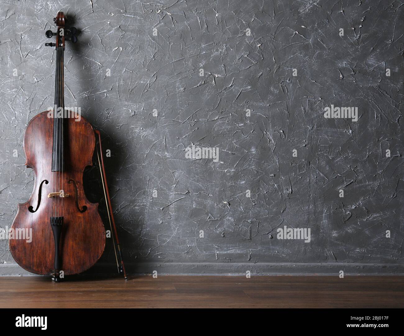 Classical cello and bow on gray wall background Stock Photo - Alamy