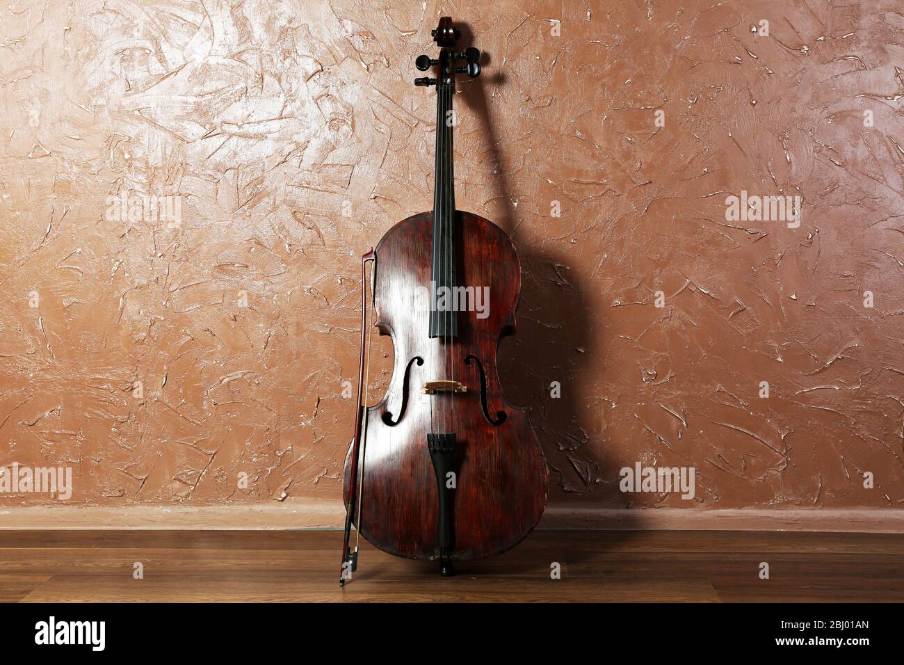 Cello on brown wall background Stock Photo - Alamy