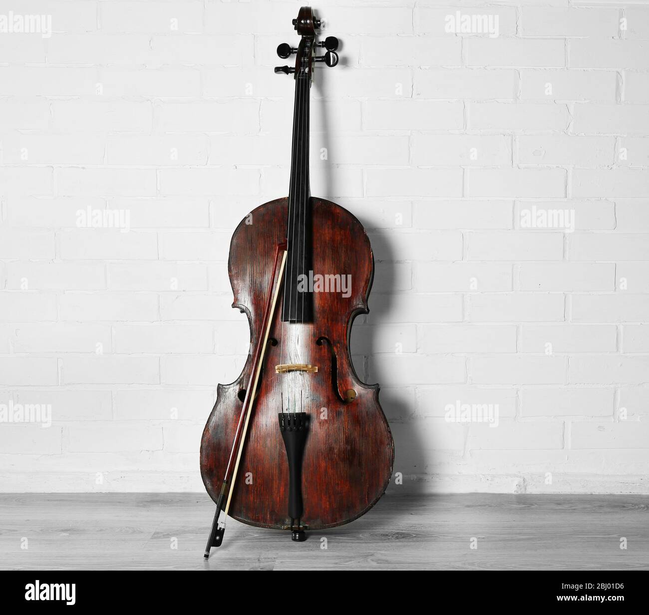 Cello on white brick wall background Stock Photo - Alamy