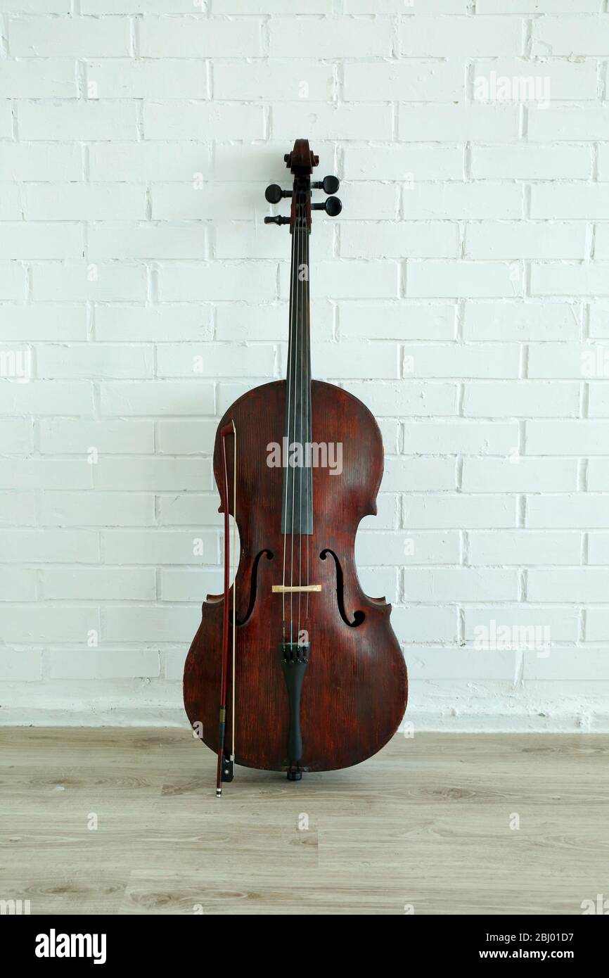 Cello on white brick wall background Stock Photo - Alamy
