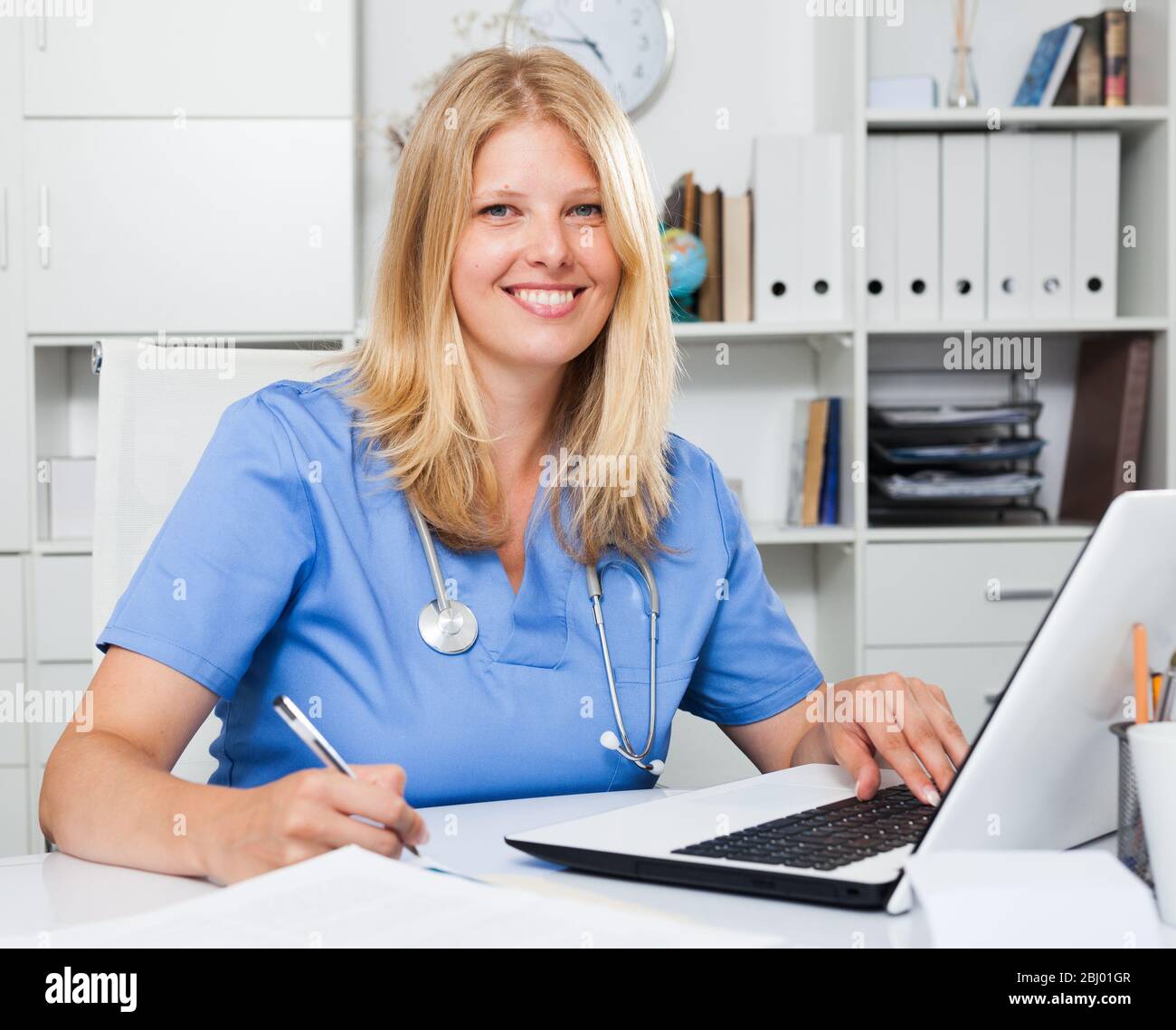 Friendly woman skilled doctor sitting at workplace in her office Stock ...
