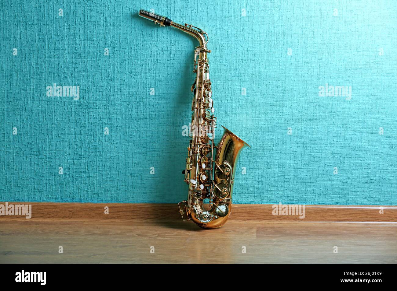 Saxophone on turquoise wallpaper background Stock Photo - Alamy