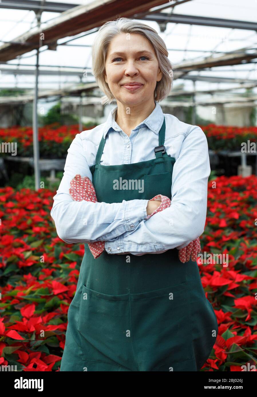 Portrait of confident skilled female florist standing with arms crossed ...
