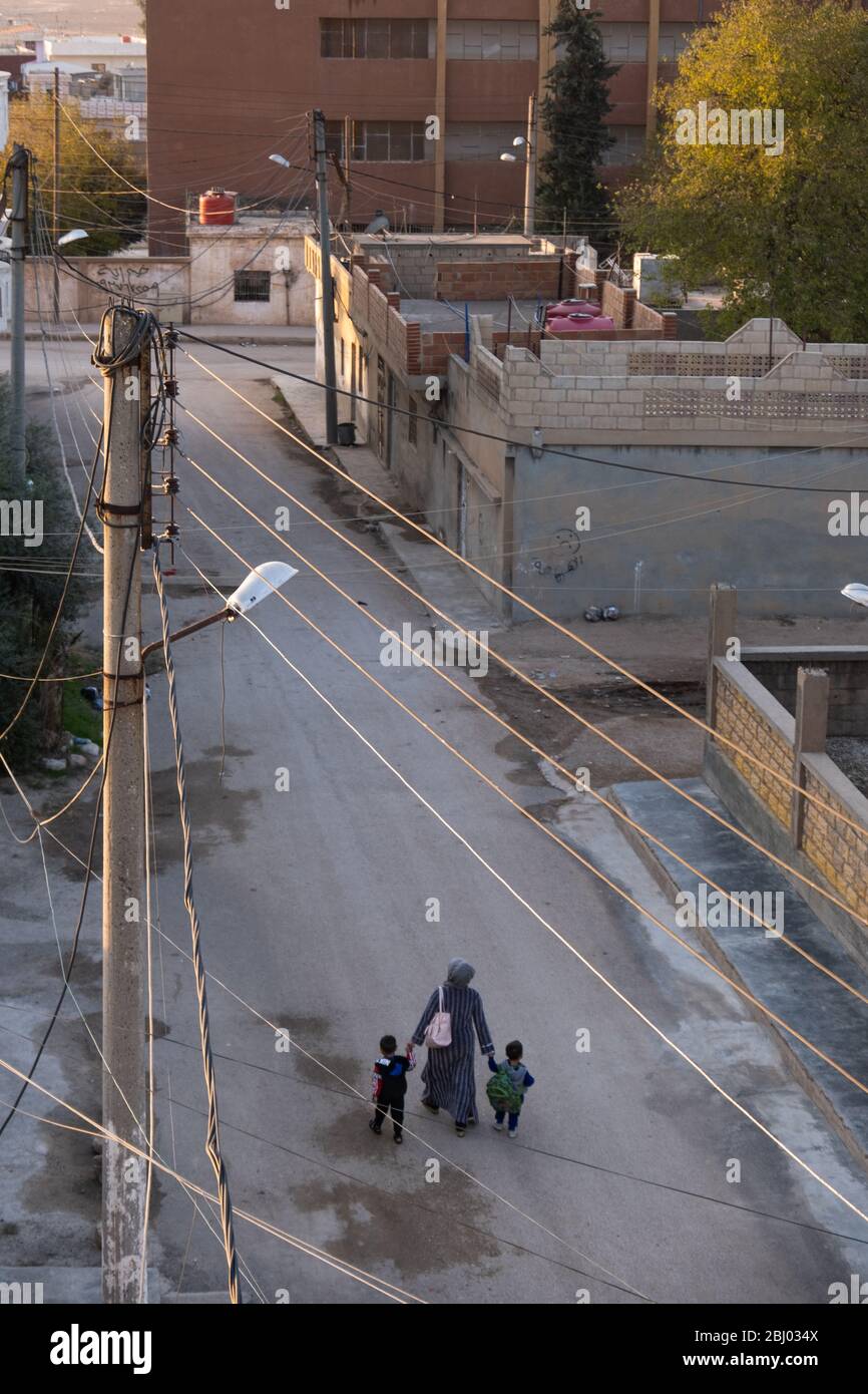 A mother and her two children walk through the quiet streets of ...