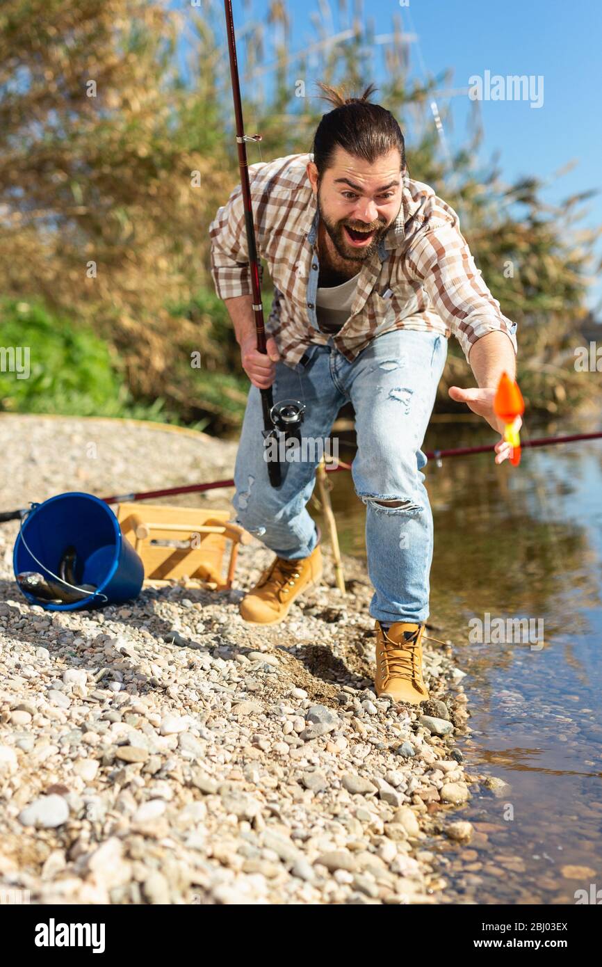 Happy fisherman pulls fish out of the river Stock Photo - Alamy