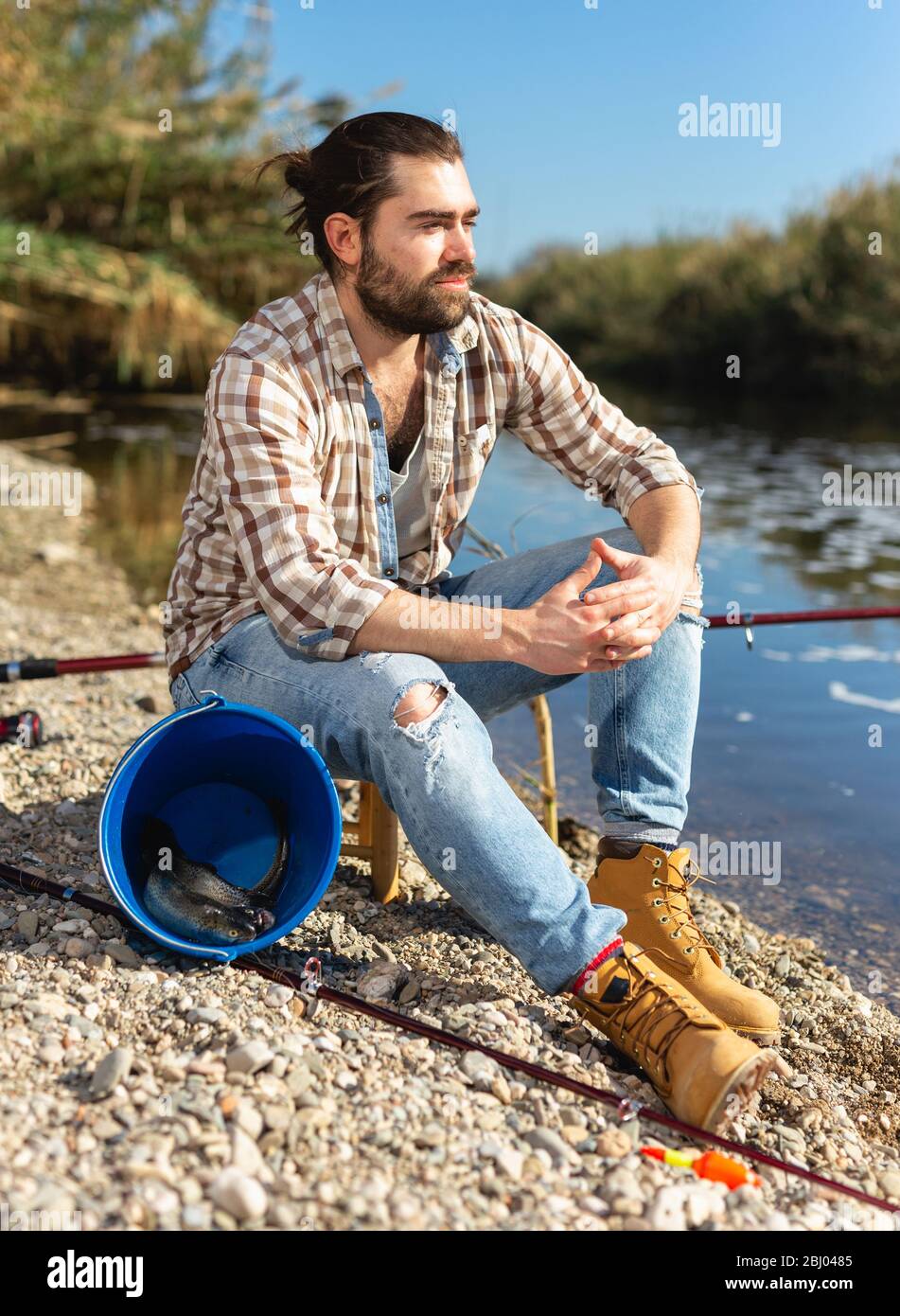 Positive adult man with rod relaxing and enjoying fishing by lakeside Stock Photo - Alamy
