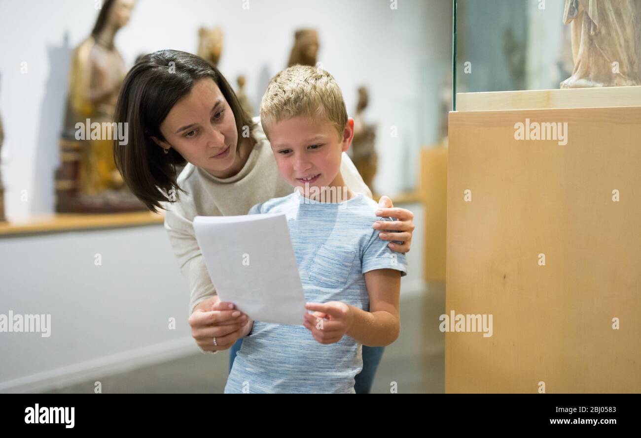 Young woman with son observing with interest sculptures exhibition in ...