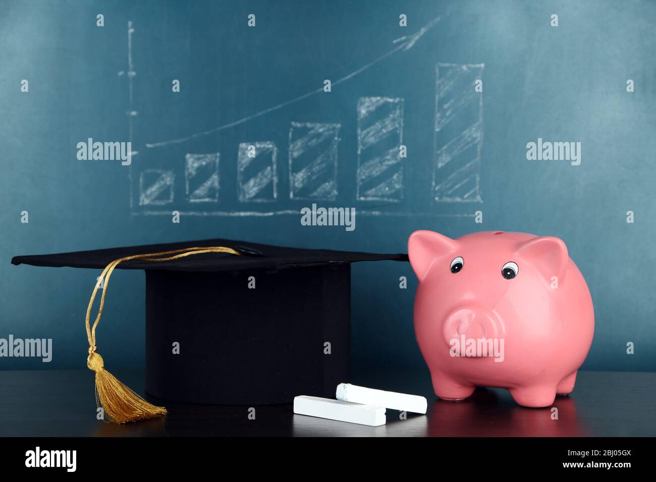 Piggy bank with grad hat on blackboard background Stock Photo - Alamy