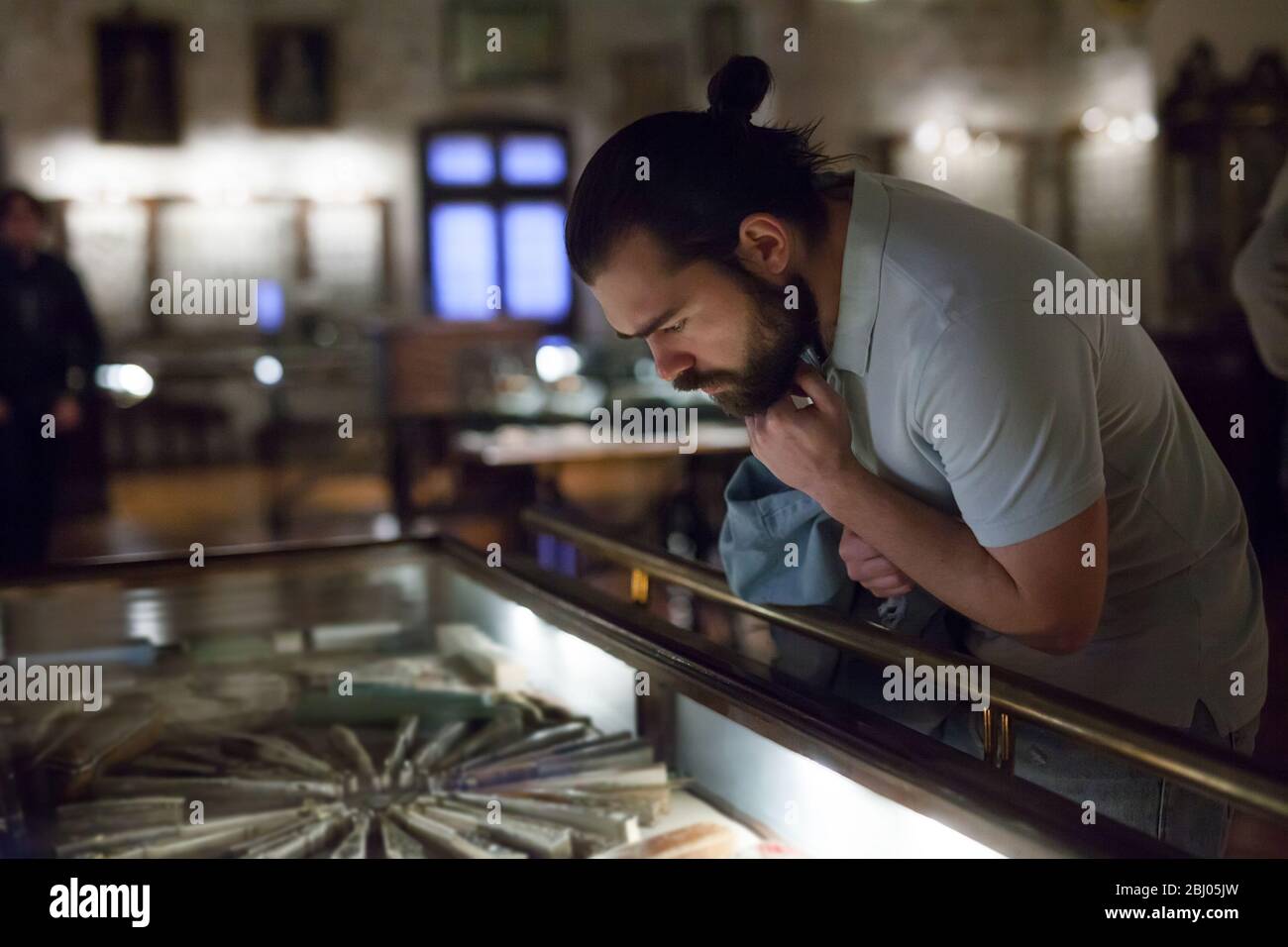 Attentive adult man exploring artworks in glass case in museum Stock ...