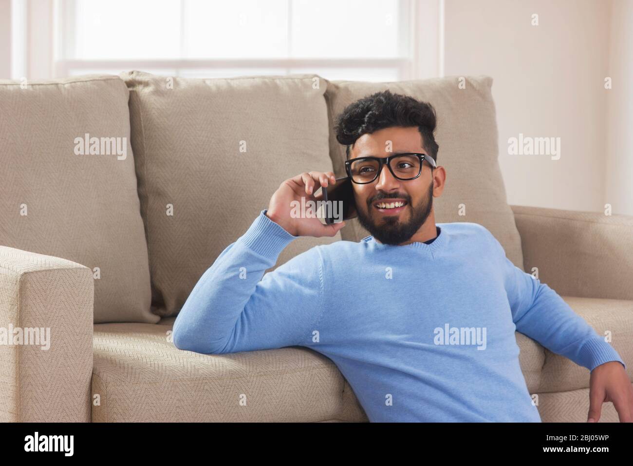 Happy man sitting in front of the sofa and talking on the phone Stock ...