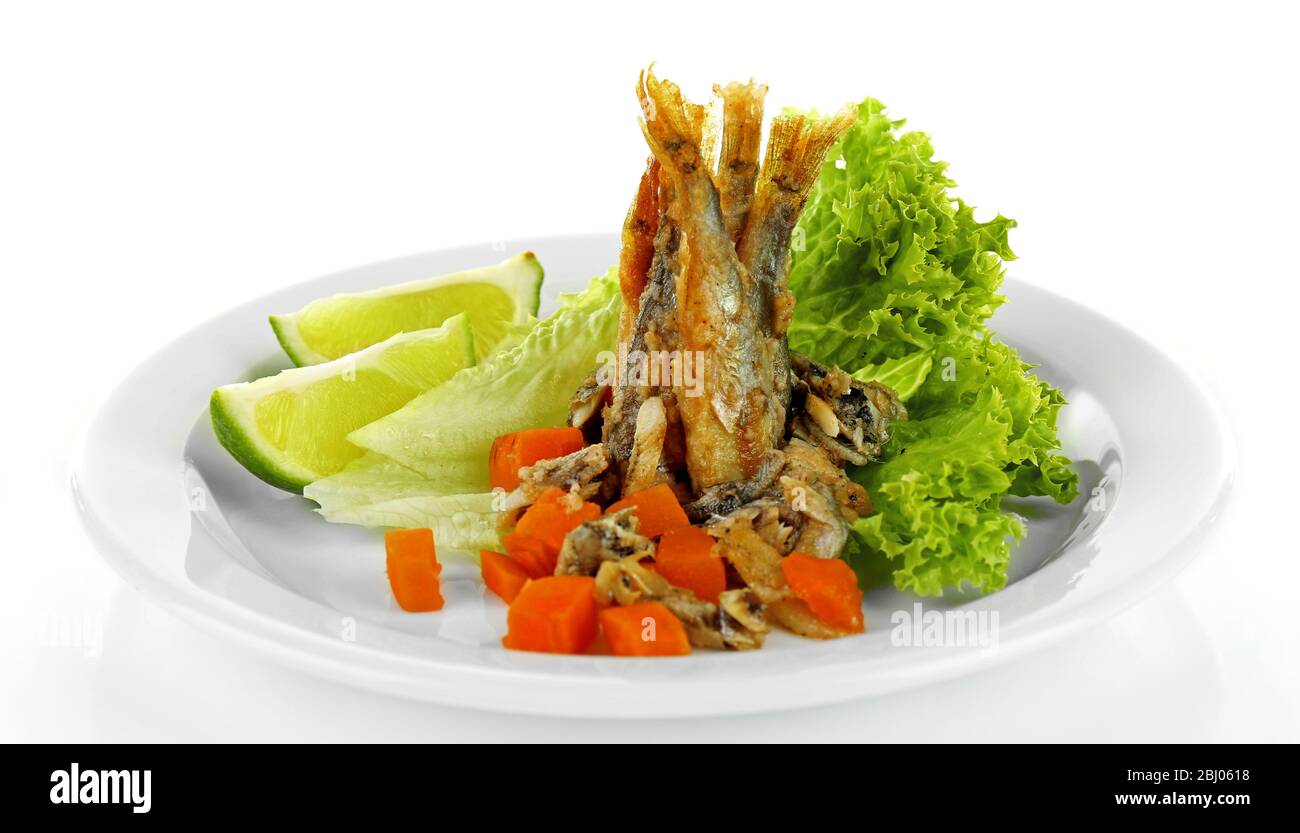 Fried small fish on plate with lettuce and lime isolated on white Stock ...