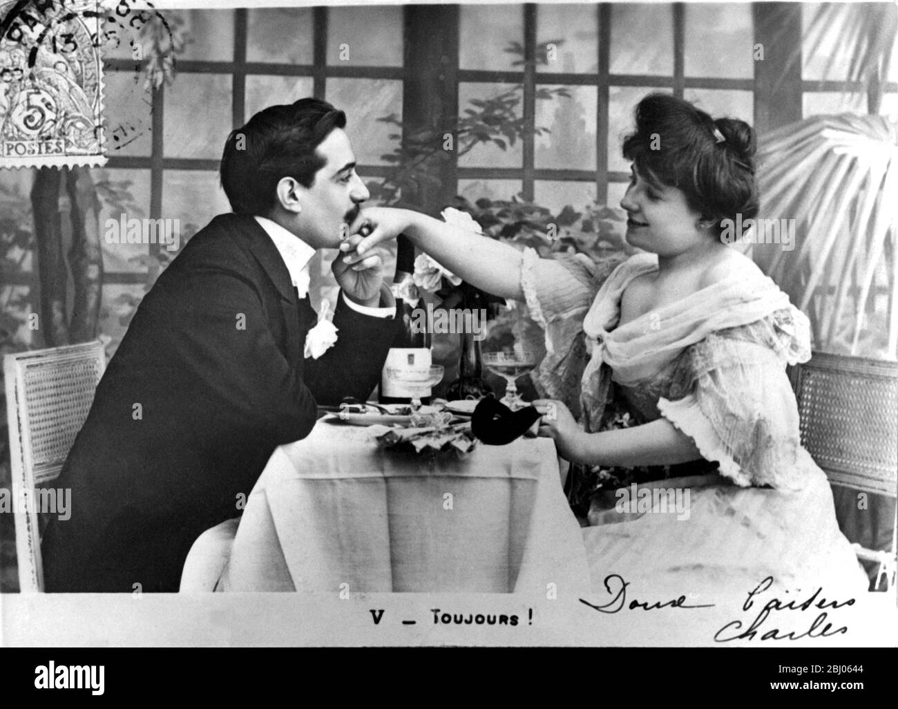 Man and woman sitting at a table with champagne and man kissing her ...