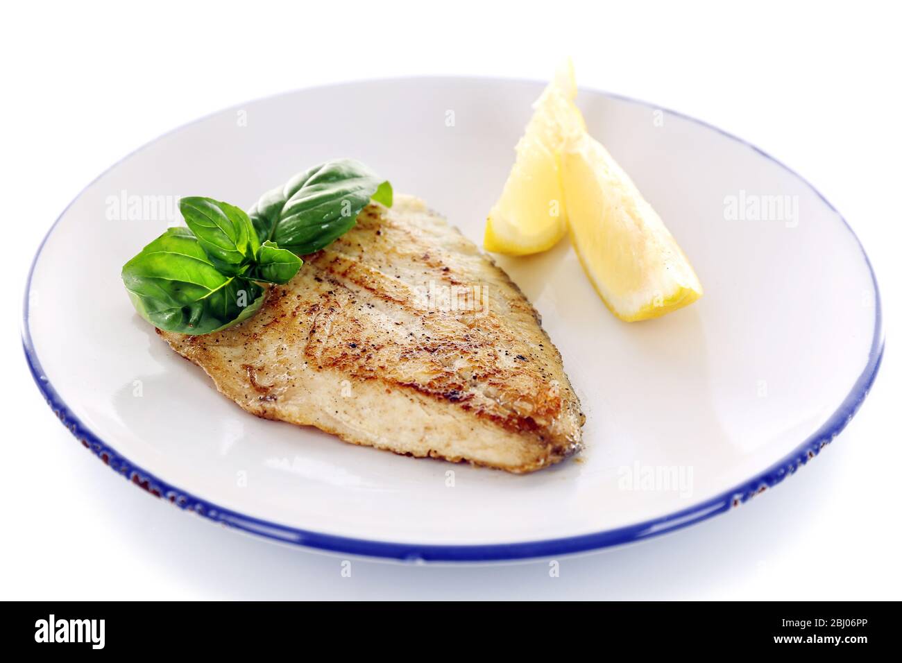 Dish of fish fillet with basil and lemon on plate isolated on white ...