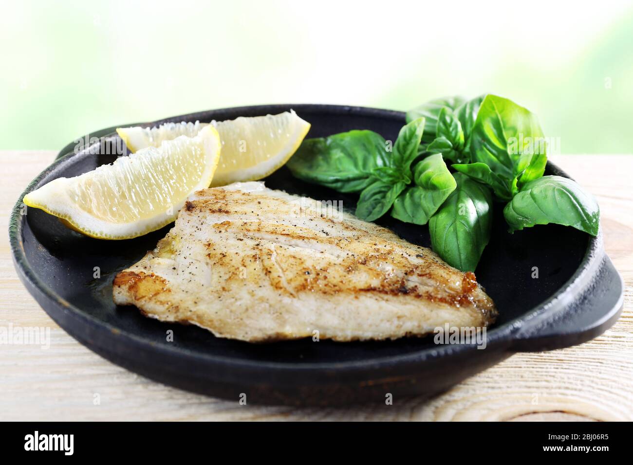 Dish of fish fillet with basil and lemon on bright background Stock ...