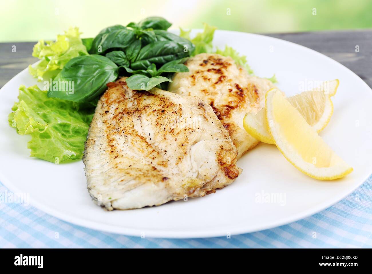 Dish of fish fillet with greens and lemon on table close up Stock Photo ...