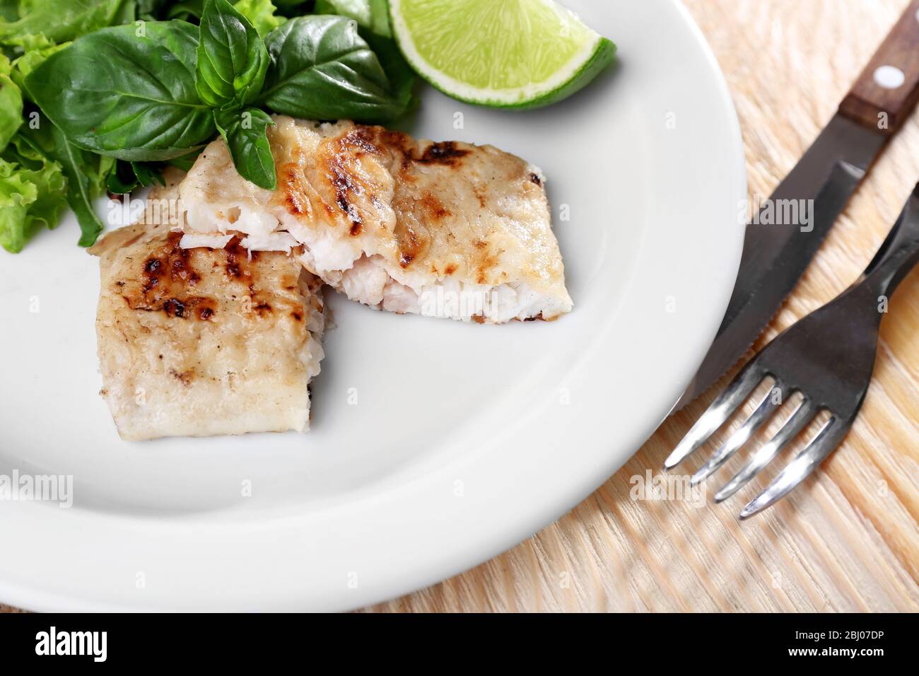 Dish of fish fillet with greens and lime on table close up Stock Photo ...