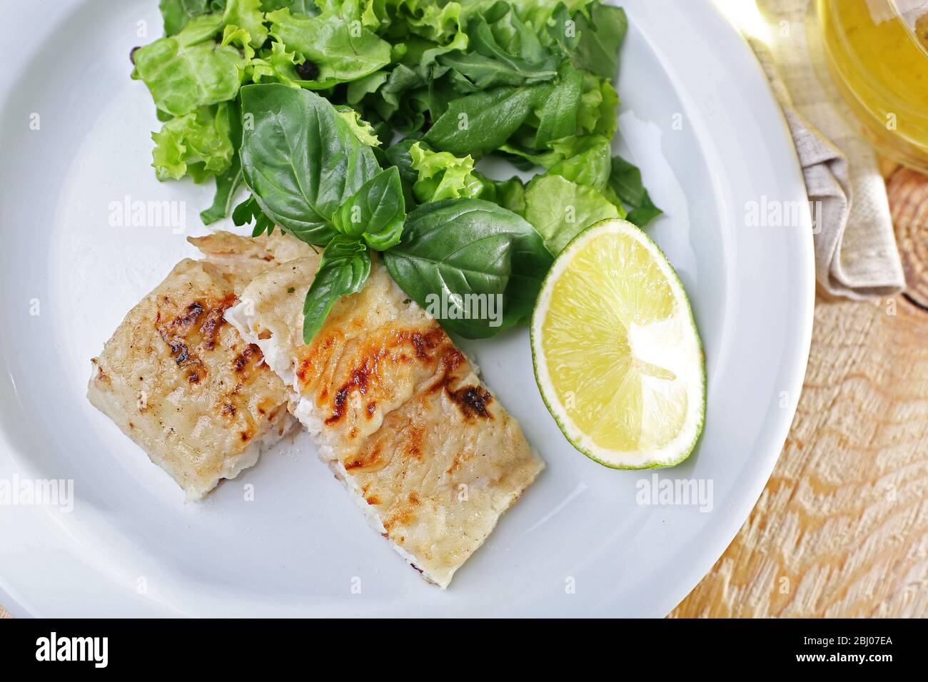 Dish of fish fillet with greens and lime on table close up Stock Photo ...