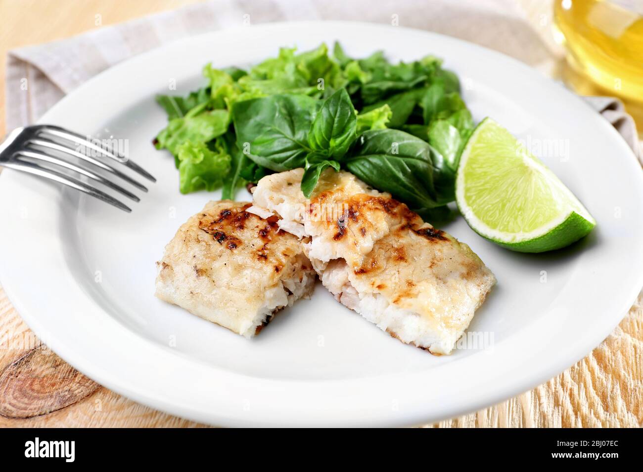 Dish of fish fillet with greens and lime on plate close up Stock Photo ...