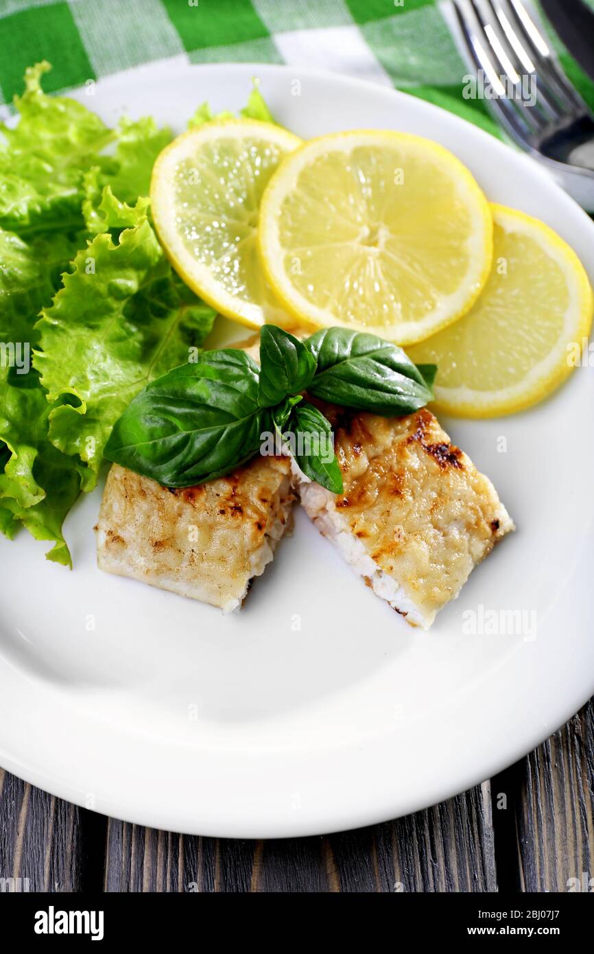 Dish of fish fillet with greens and lemon on plate close up Stock Photo ...