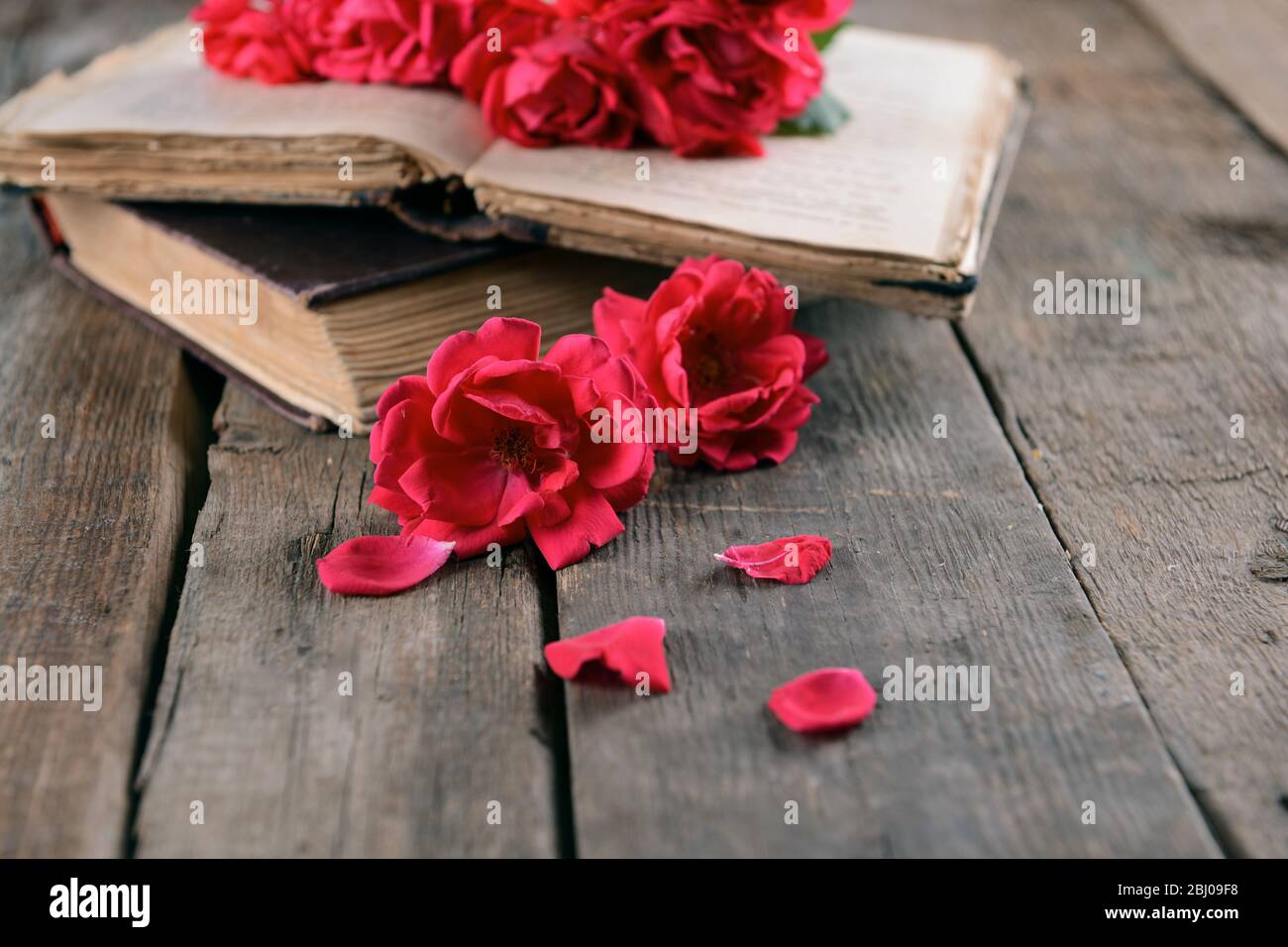 Old books with beautiful flowers on wooden table close up Stock Photo ...