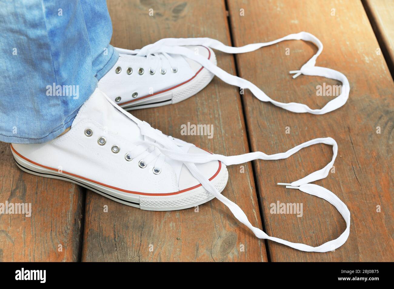 Female feet in gum shoes on wooden floor background Stock Photo - Alamy