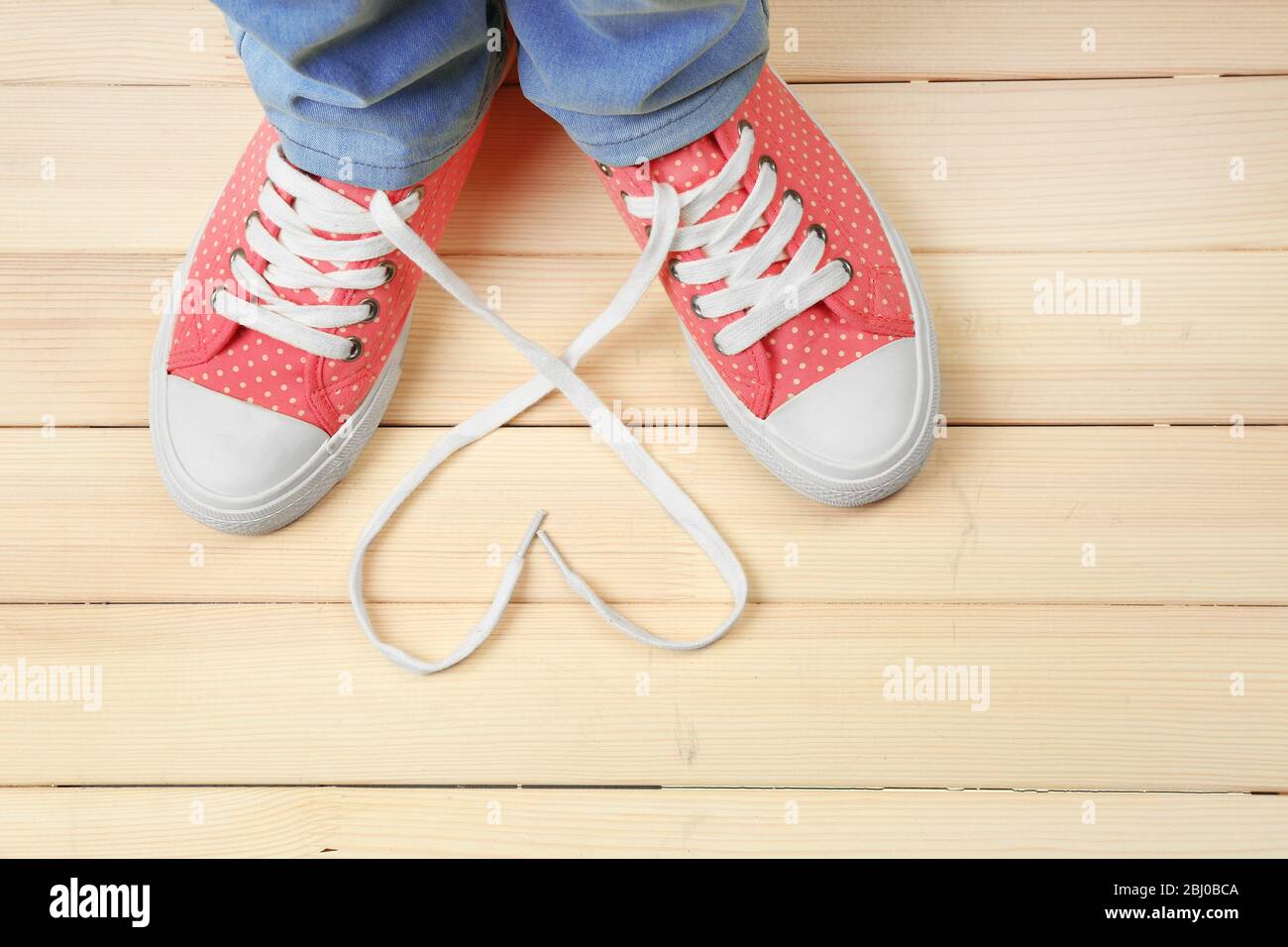 Female feet in gum shoes on wooden floor background Stock Photo - Alamy