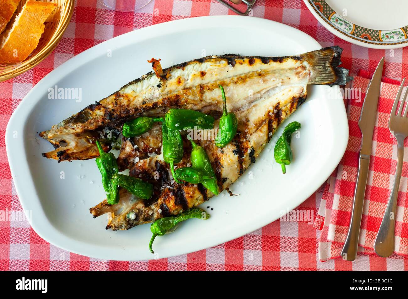 Seafood dish, grilled sea bass fish with green peppers on platter on ...