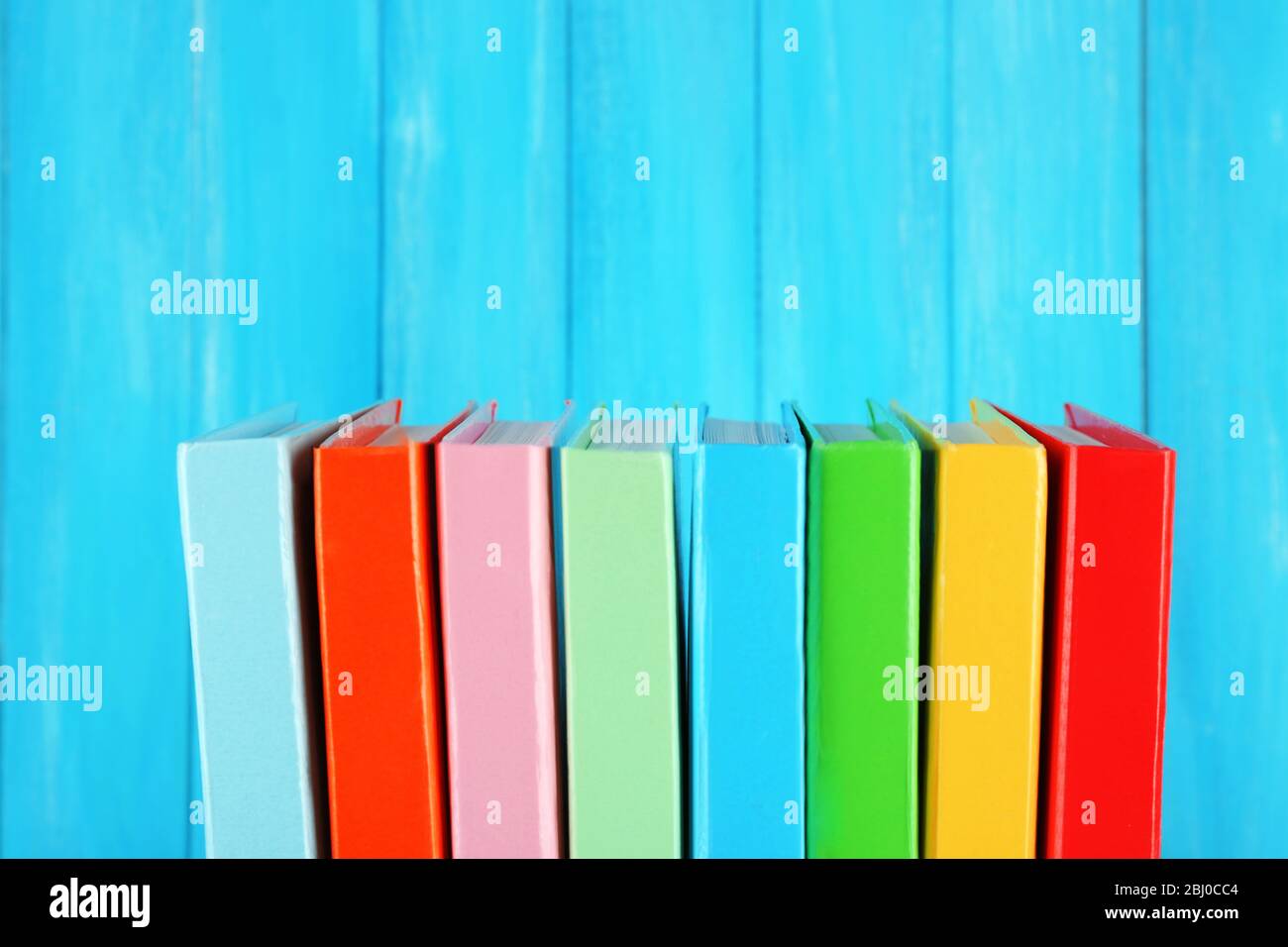 Colorful books on turquoise wooden background Stock Photo - Alamy