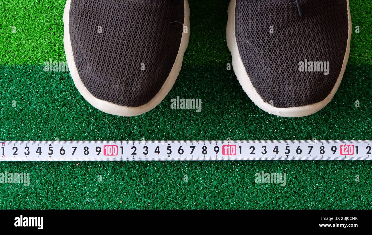 The tip of a pair of black shoes with a measuring tape in front ...