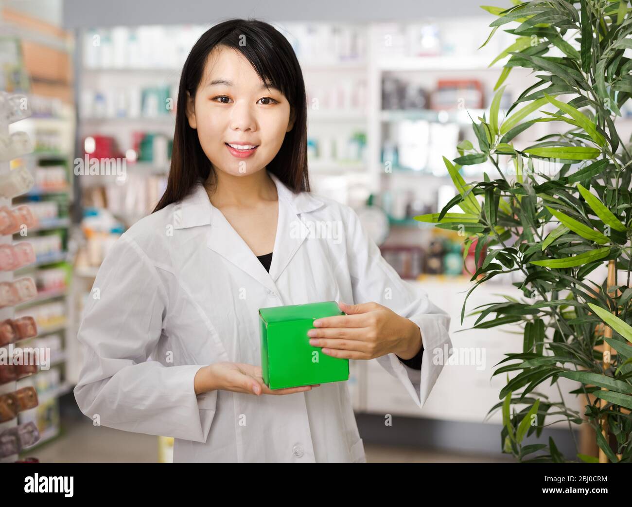 Smiling chinese female pharmacist demonstrating assortment of pharmacy ...