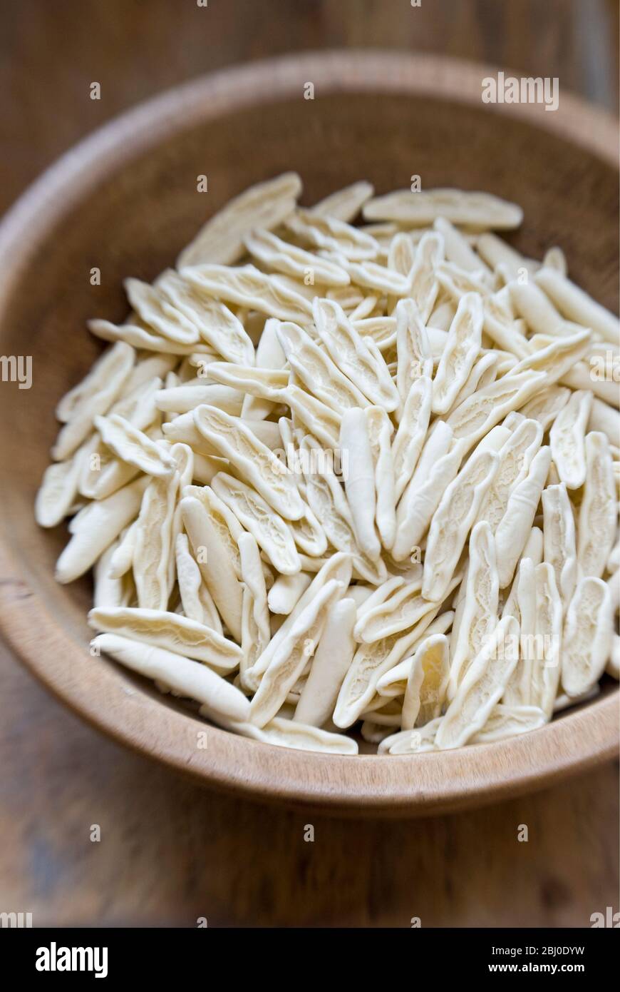 Raw cicatelli pasta shapes, in old wooden bowl on wooden surface Stock ...