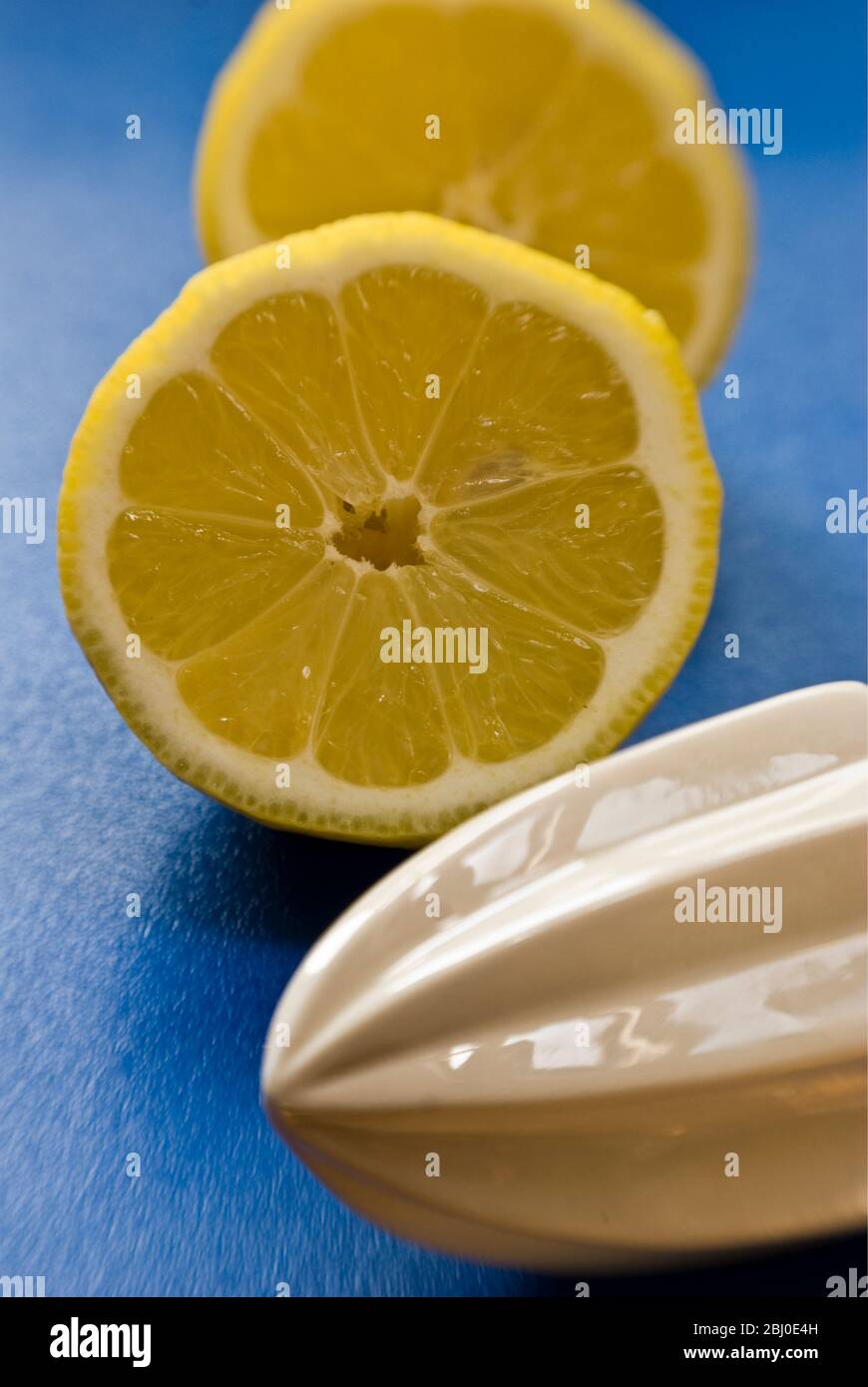 Squeezing halved elmon with reamer on blue surface Stock Photo - Alamy