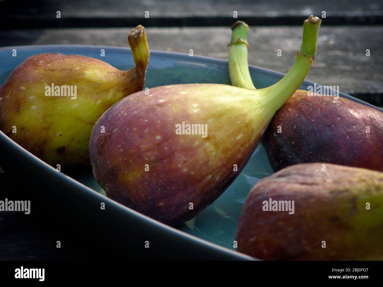 Fresh figs in pottery bowl outside on garden table Stock Photo - Alamy