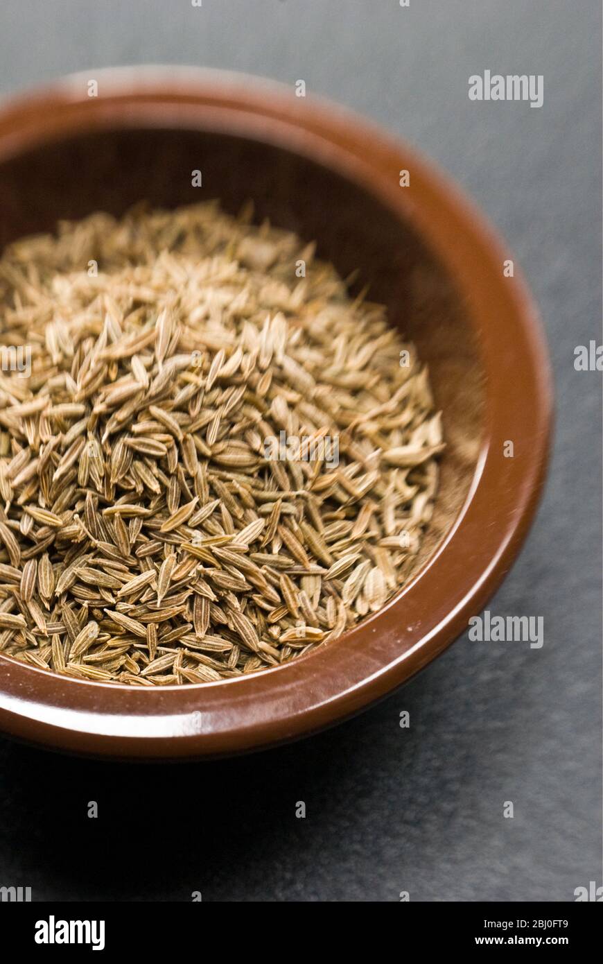 Whole dried cumin seeds in small bowl Stock Photo - Alamy