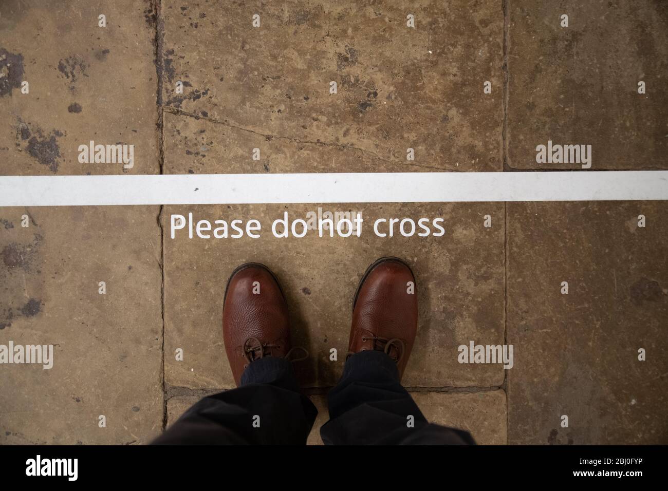 Feet standing at 'do not cross' line Stock Photo - Alamy
