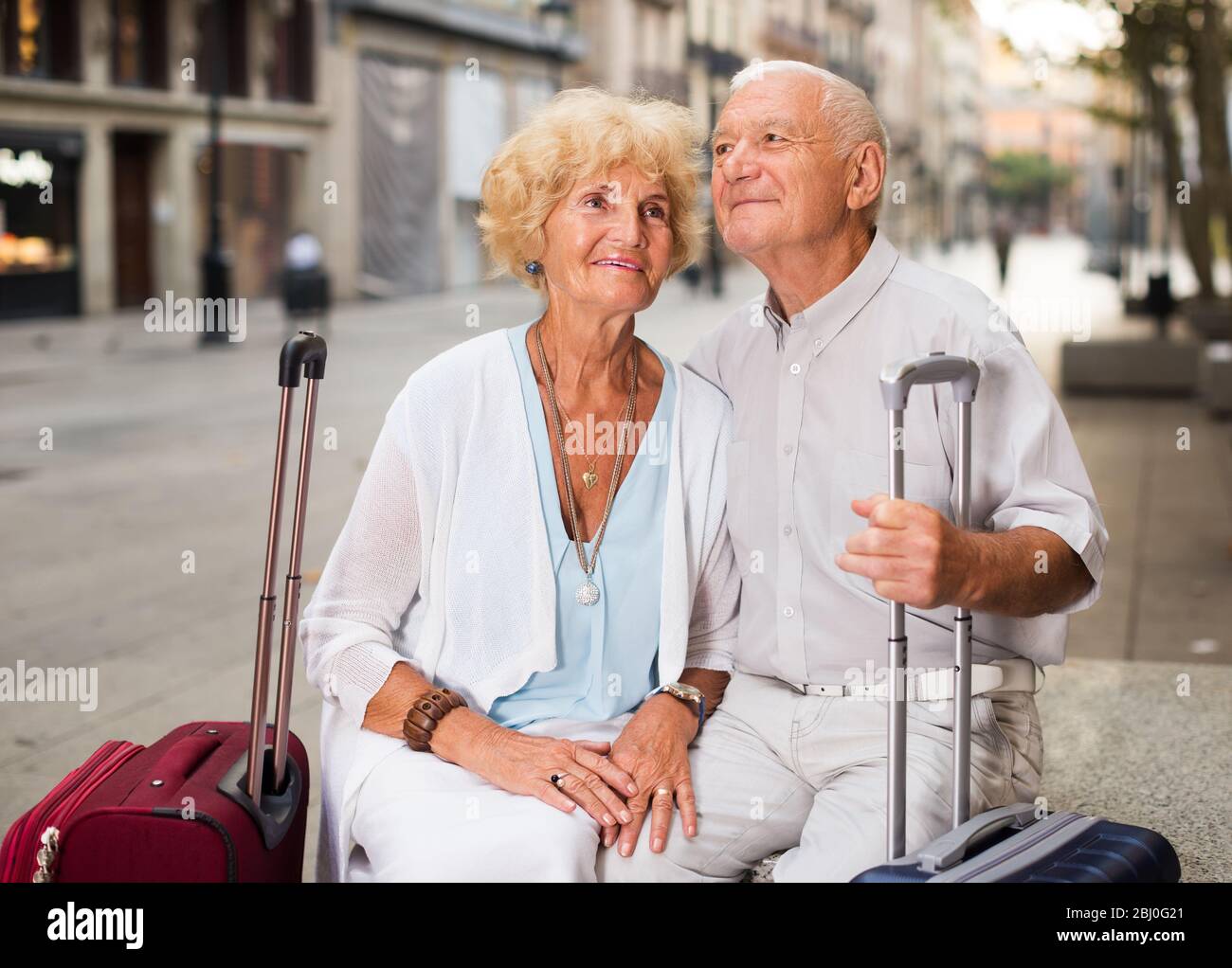 Happy loving mature spouses enjoying joint vacation sitting on bench ...