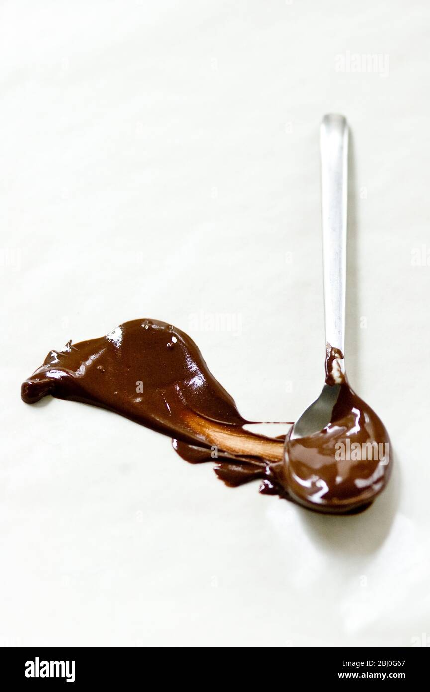 Melted chocolate smeared across white surface with a spoon leaving a ...