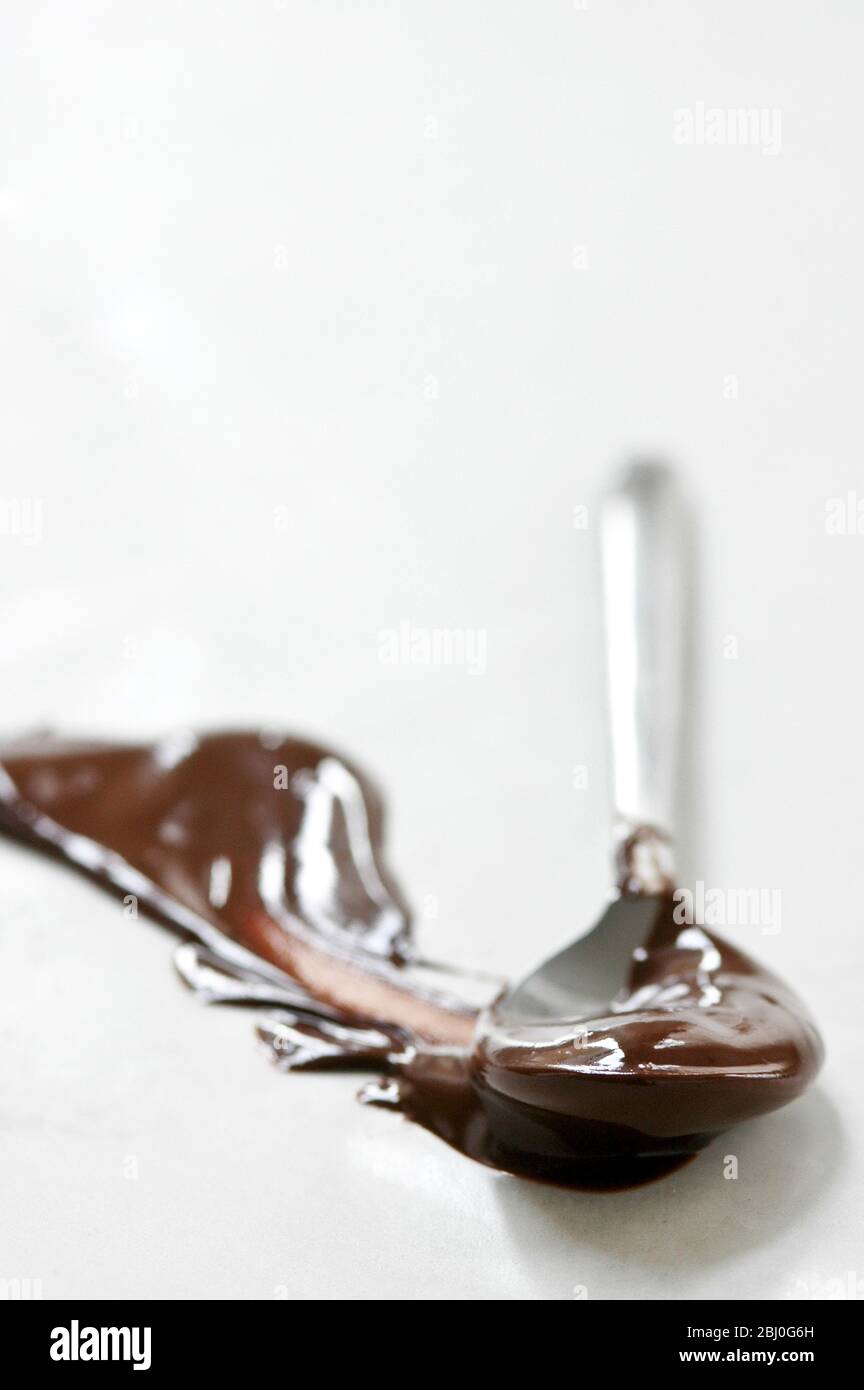 Melted chocolate smeared across white surface with a spoon leaving a ...