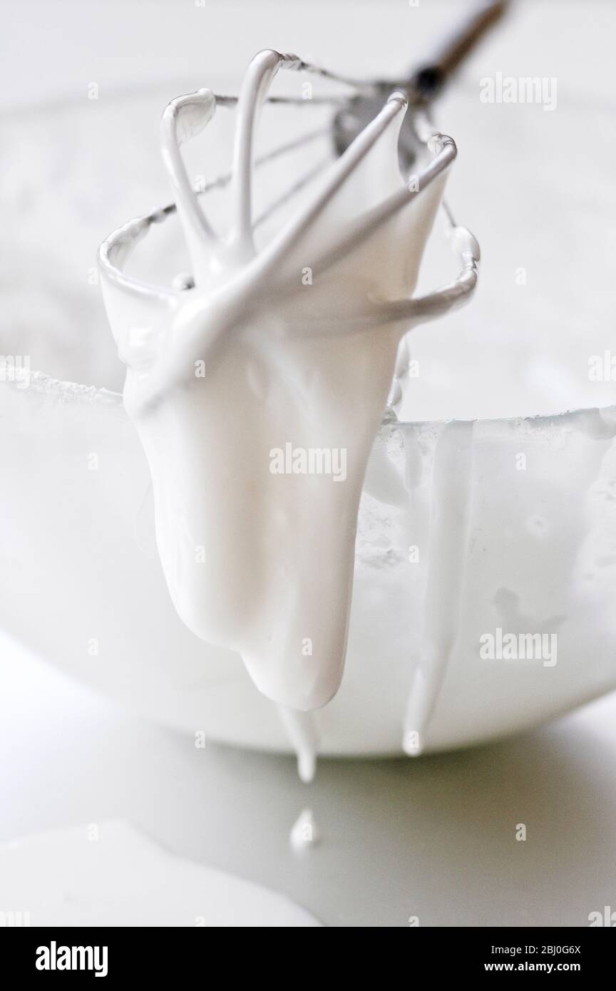 Bowl of white icing with dripping balloon whisk Stock Photo - Alamy