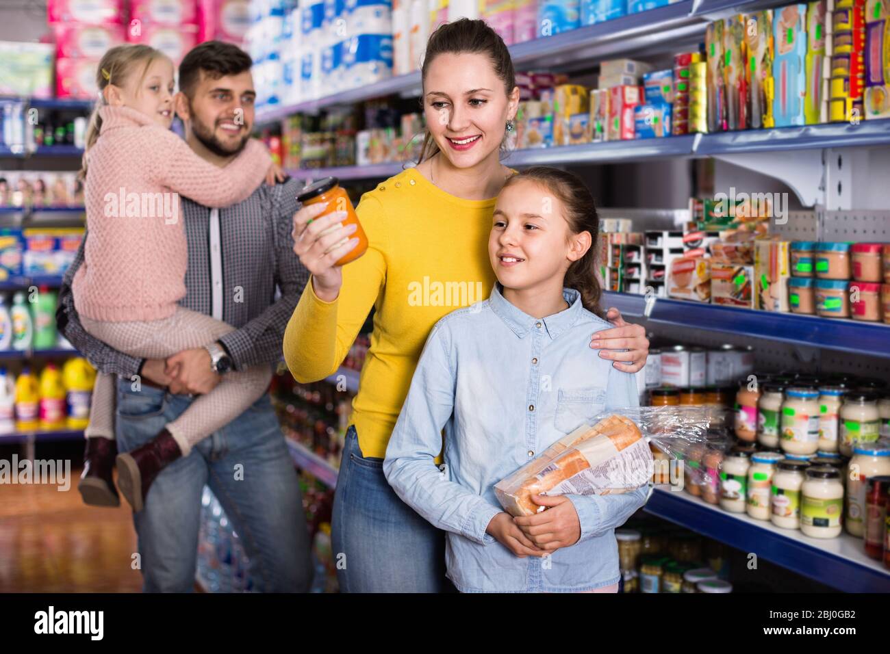 Happy glad positive family with two little girls buying food products ...