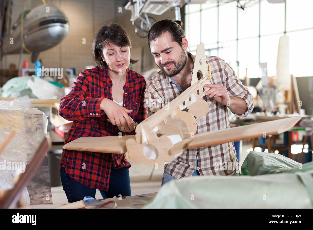 Female and male hobbyists engaged in creating plane models in aircraft ...
