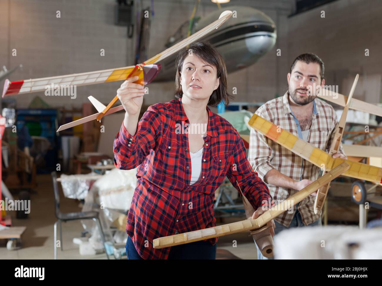 Portrait of happy female and male hobbyists with plane models created ...
