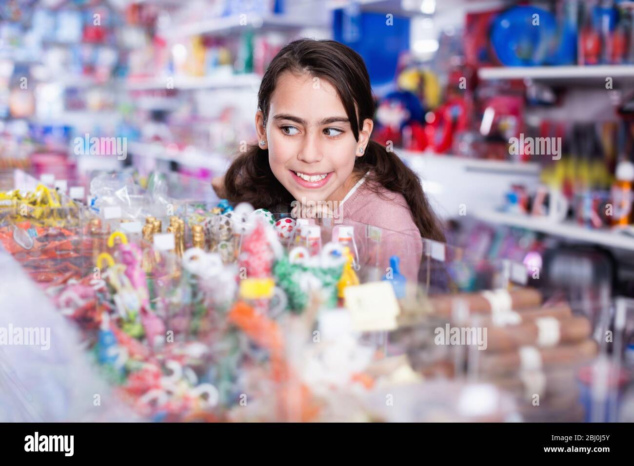 Emotional happy smiling small girl choosing sweet candies in the candy ...