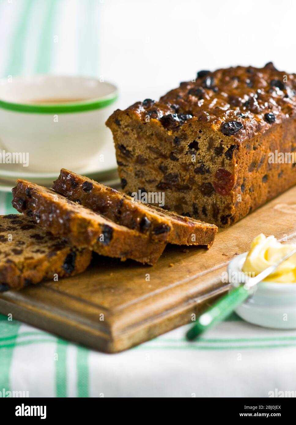 Traditional style fruit tea loaf sliced and served with butter and ...