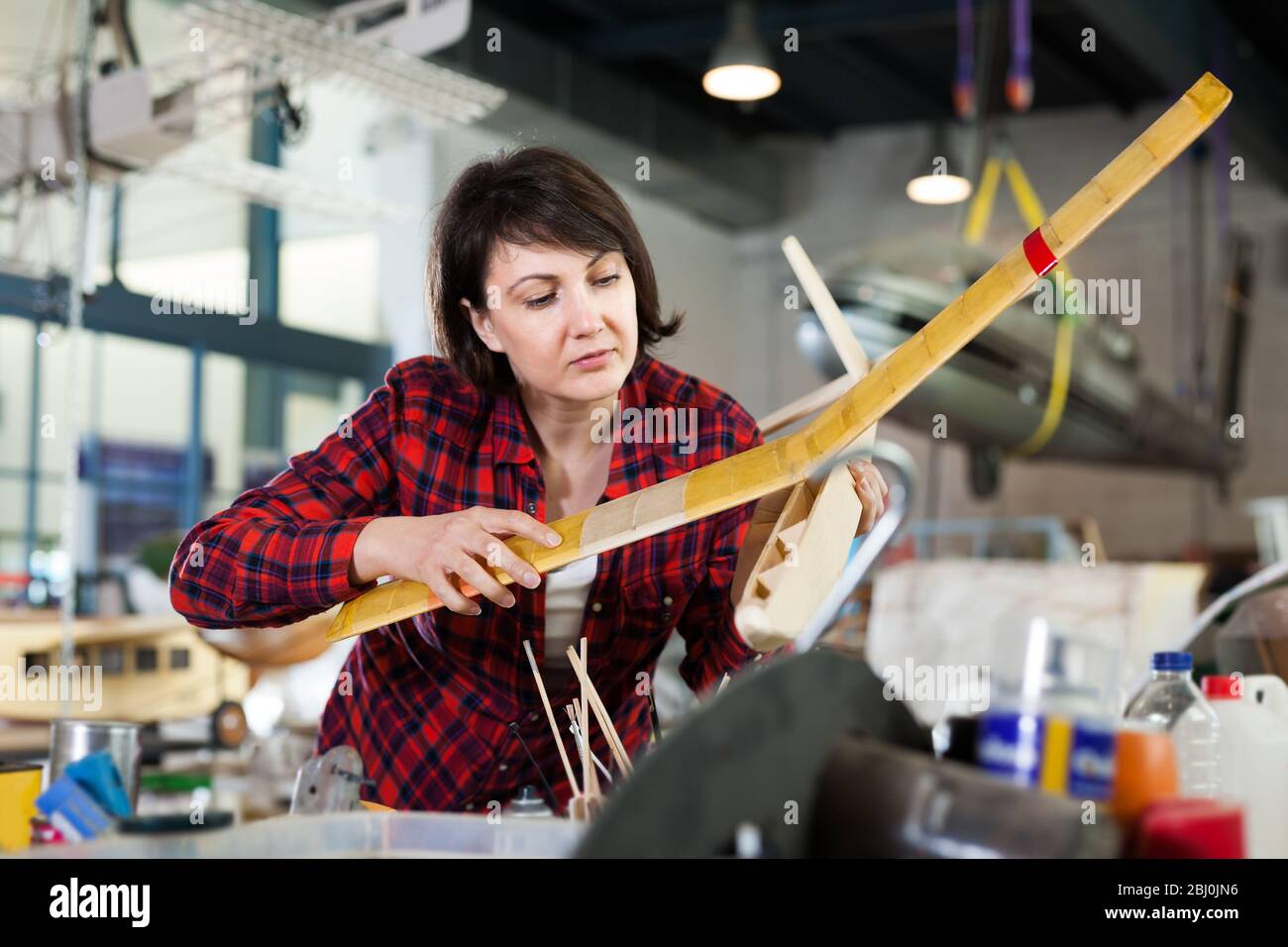 Young female enjoying her hobby - modeling light airplanes in aircraft ...