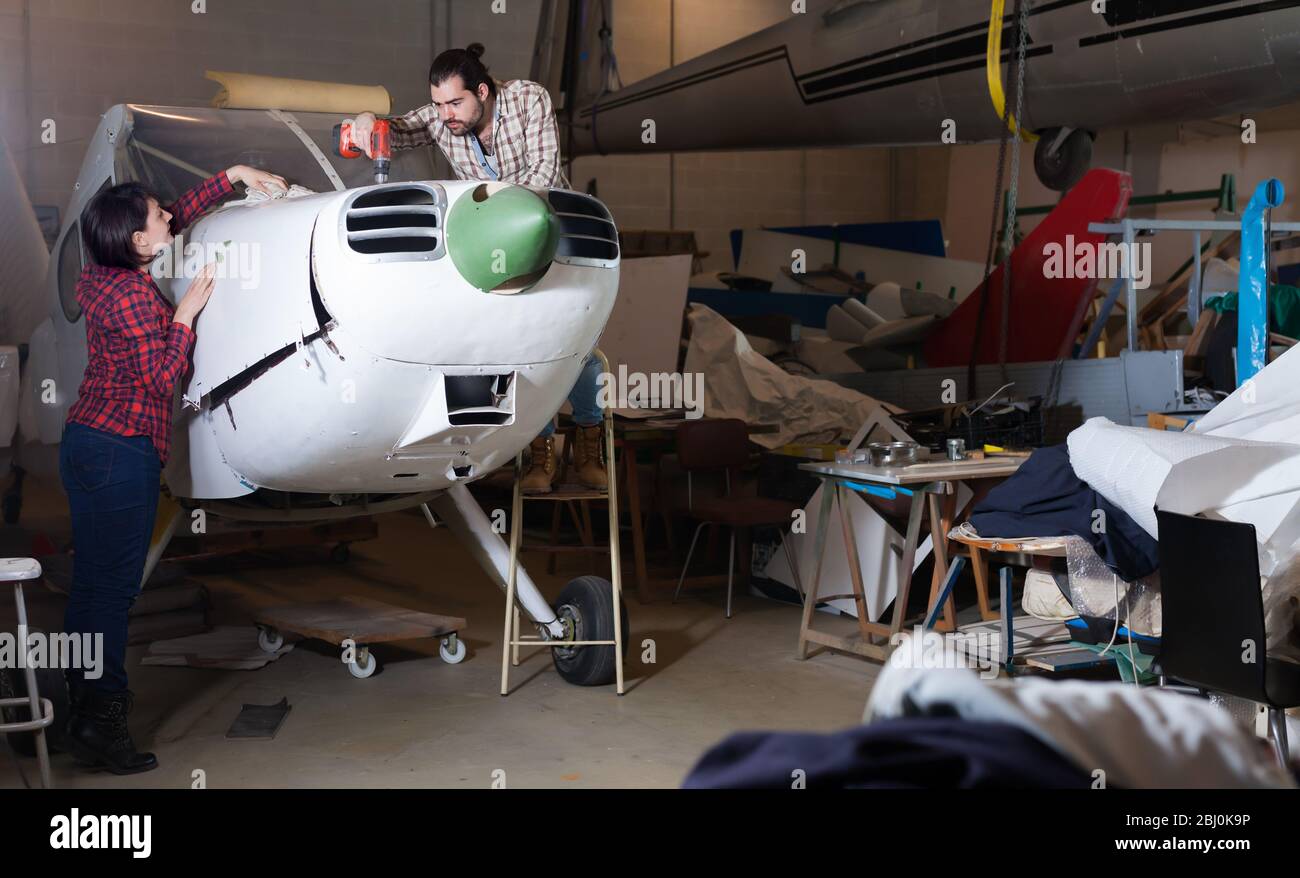 Positive male aircraft enthusiast with female assistant working in ...