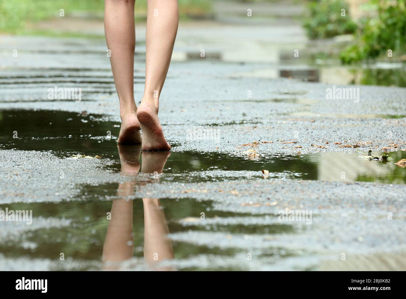 Woman walking barefoot through puddle outdoors Stock Photo - Alamy