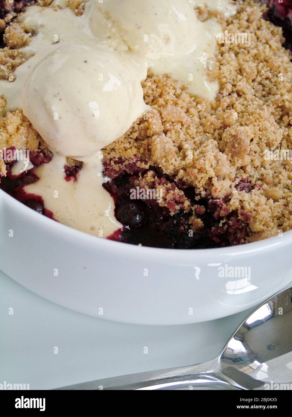 Classic blackcurrant crumble with vanilla custard Stock Photo - Alamy