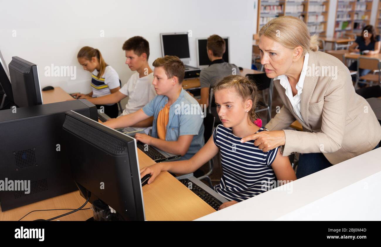 Schoolgirl using computer and teacher teaching she in classroom Stock ...