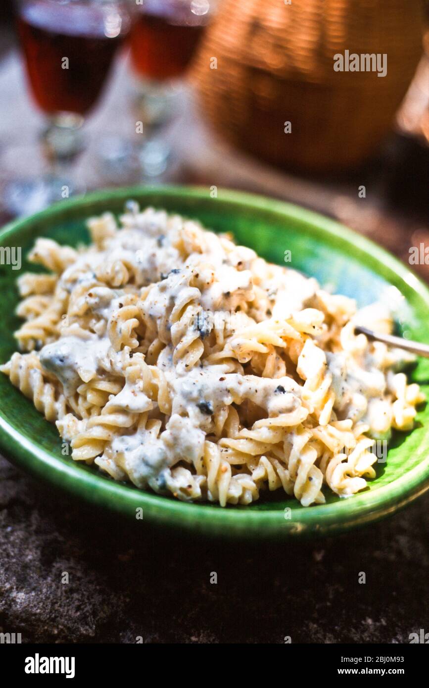 Dish of fusilli pasta with blue cheese creamy dressing on table outside ...